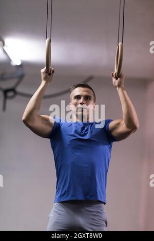 Fitness handsome man doing dipping exercise using rings in the gym ...