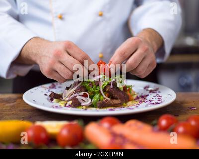 cook chef decorating garnishing prepared meal dish on the plate in ...