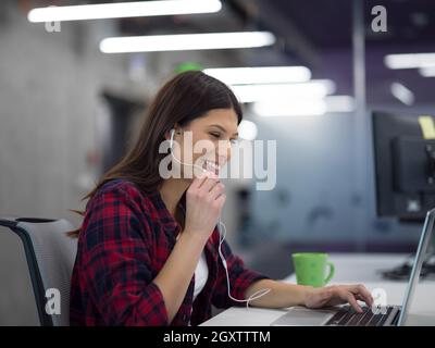 young female software developer using desktop computer while writing ...