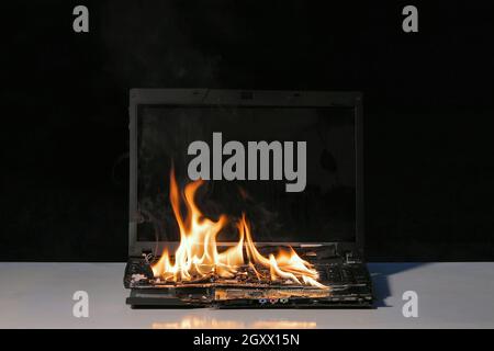 Laptop burning in flames on a desk, fire hazard. losing valuable data ...