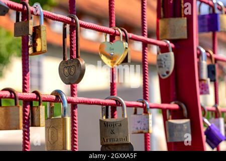 A romantic red heart lock on an urban industrial bridge railing ...