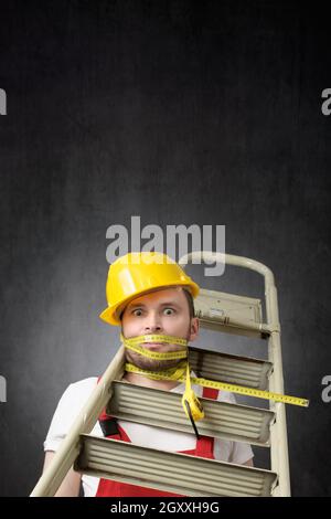 Clumsy construction worker with ladder and measure tape Stock Photo - Alamy