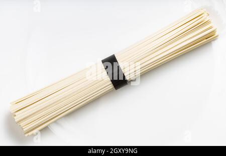 bunch of dried round Udon noodles from wheat flour on white plate Stock ...