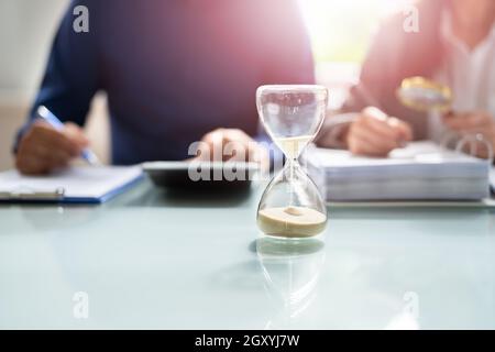 Hourglass And Time Crunch With Document In Office Stock Photo - Alamy