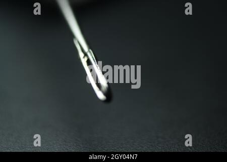 Macro photograph of sewing needle. Small needle with empty eyelet ...