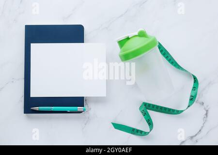 Blank white paper note and fitness equipments on white marble ...