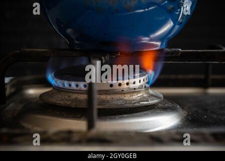 Flames of natural gas stove boiling water in a blue kettle at home ...