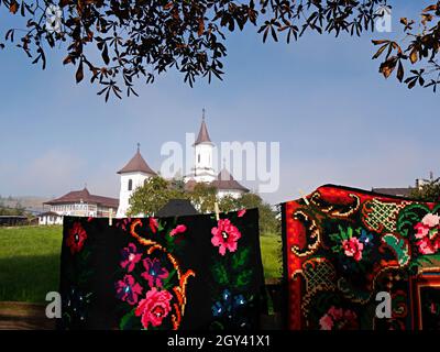 Bright, traditional rugs with painted monastery in background, Romania ...