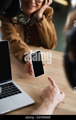 cropped view of radio host pointing at notebook near colleague in ...
