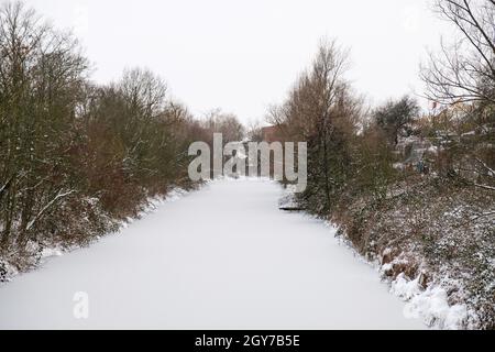 The partly frozen canal in Leipzig with lots of snow on the banks in ...