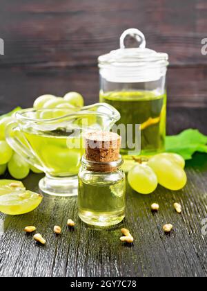 Grape oil in a bottle, gravy boat and jar, berries of green grapes on ...