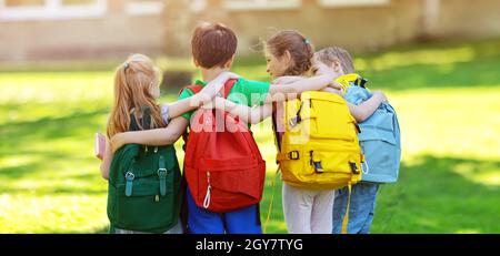 Child with rucksacks standing in the park near school. Pupils with ...