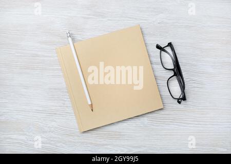 Photo of blank closed sketchbook, pencil and glasses on wooden ...