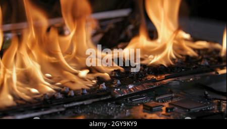 Laptop burning in flames on a desk, fire hazard. losing valuable data ...
