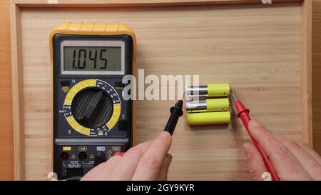Testing AA battery cell with digital multimeter tool, voltage check ...