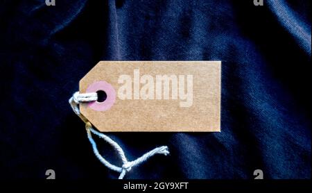 brown cardboard label with a thin cord on a black fabric background ...