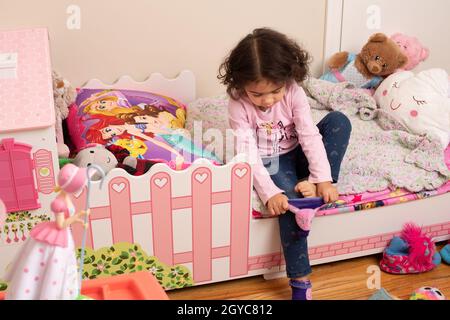 child girl pulling sock socks off dressing feet clothes not liking ...