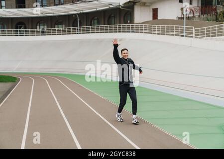 Happy man in earphones waving hand while taking video call on laptop at ...