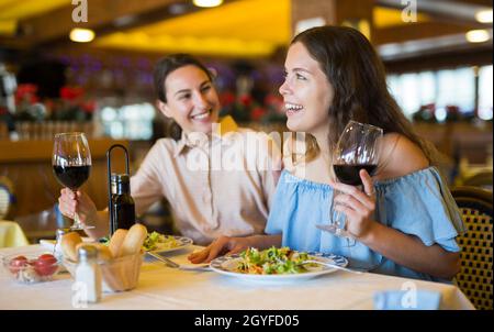 Two girls are discussing something fun at a table in a restaurant Stock ...