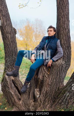 Tall handsome man climbing on the tree in yellow autumn forest Stock ...