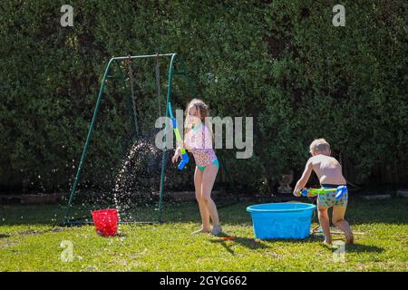 Aussie kids enjoying backyard water fight in summer Stock Photo - Alamy