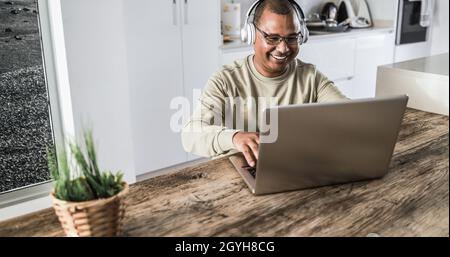 Hispanic senior man wearing call center agent headset at night smiling ...