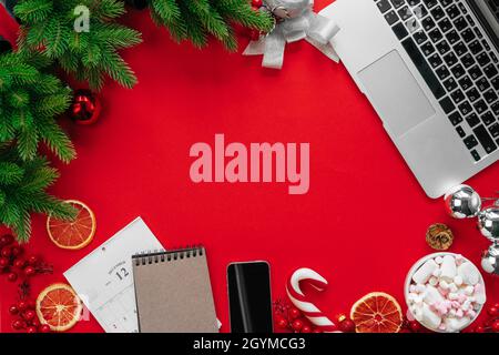 Laptop with fur tree branches and christmas decorations on red ...