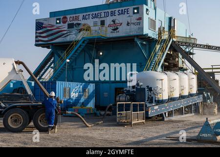 Oilfield workers transferring dry cement from their truck to the oil ...