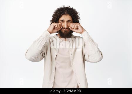 Sad and gloomy man sulking, looking bored at upper left corner ...