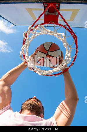 man dunking basketball ball through net ring with hands, copy space ...