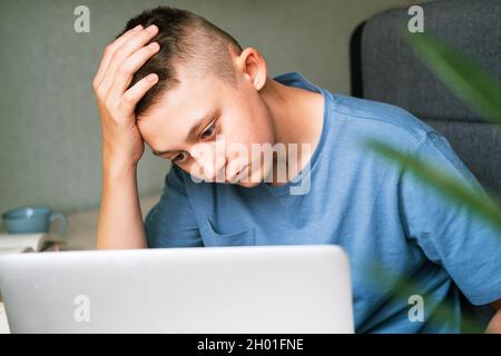 Teen boy tiredly looking at the computer screen Stock Photo - Alamy