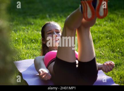 A teenage girl doing abdominal crunches. A girl performs exercises for ...