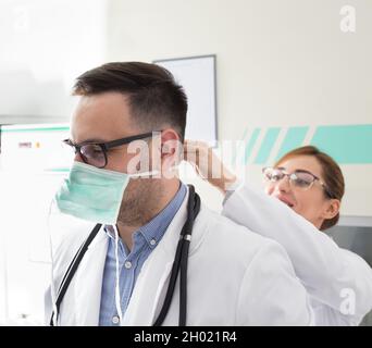 woman tying tie on handsome businessman in black suit isolated on grey ...