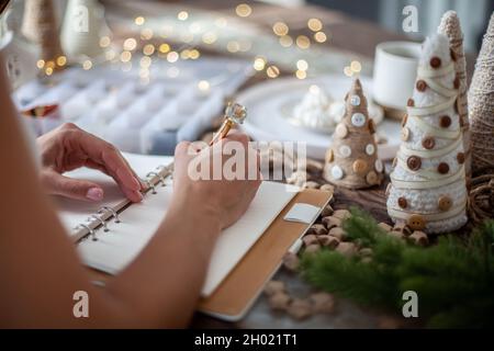 Young woman writing plans or goals for New Year 2021 while her daughter ...