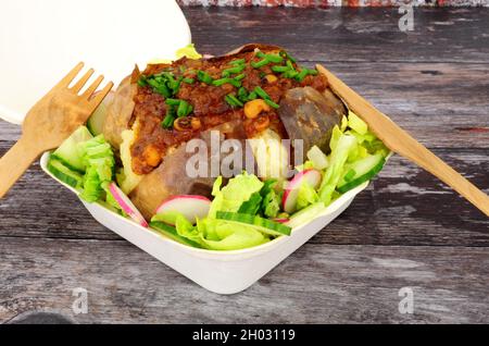 Chilli beef filled baked jacket potato with fresh salad in a take away ...