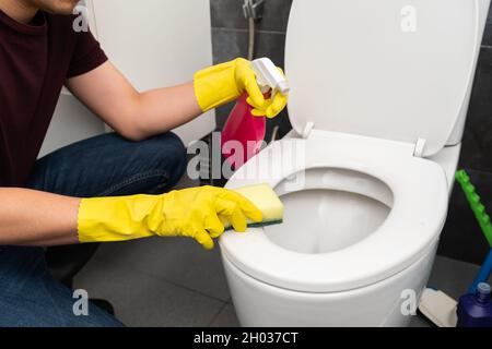 Young man cleaning toilet bowl with rag in bathroom Stock Photo - Alamy