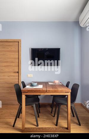 Stylish dining room interior with wooden table black chairs and TV set Stock Photo Alamy