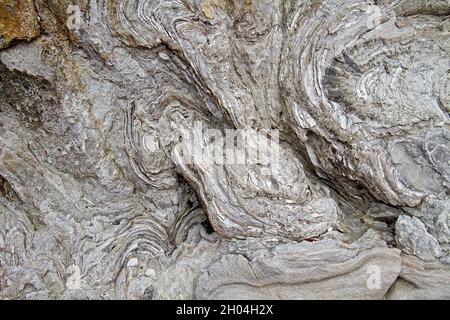 Detail of grey, deformed and curved layers in rock, caused by ...