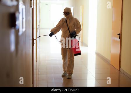 Person in hazmat suit disinfects living room with spray gun Stock Photo ...