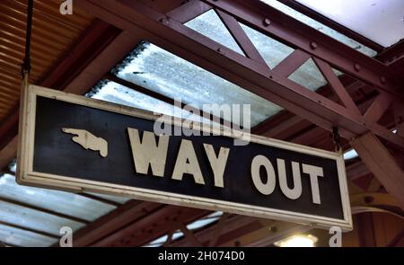Old Way Out sign with hand pointing finger on old white tiles in train ...