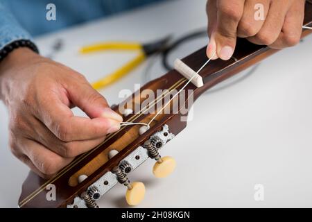 Restring classical guitar concept. The man restring his classical ...