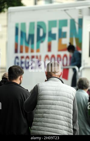 People queue in front of a vaccination center to get vaccinated against ...