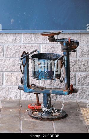 An unusual steampunk style trash can with mechanisms, gears and chains ...