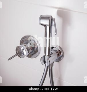 Using of bidet shower with a white toilet. Bidet shower in male hand ...