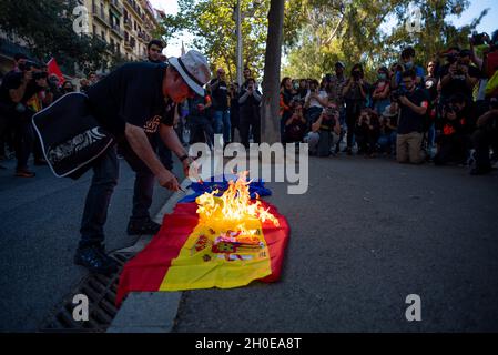A man burns a Spanish flag during a rally against the presence of King ...