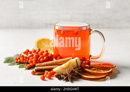 Composition with cup of tasty rowan tea, berries and lemon on blue ...