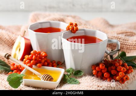 Composition with cups of tasty rowan tea, honey and berries on light ...