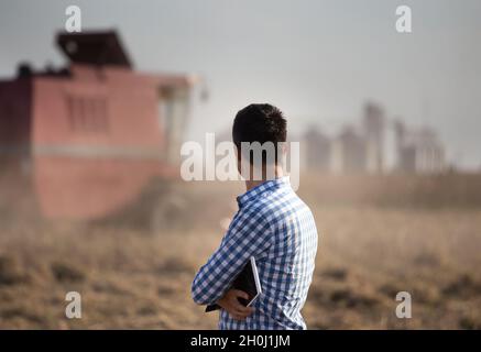 Farmer standing in soybean field looking at notebook and drone Stock ...