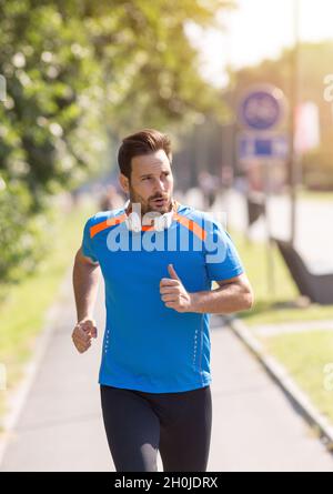 Satisfied handsome man running in park. Urban morning jogging Stock ...