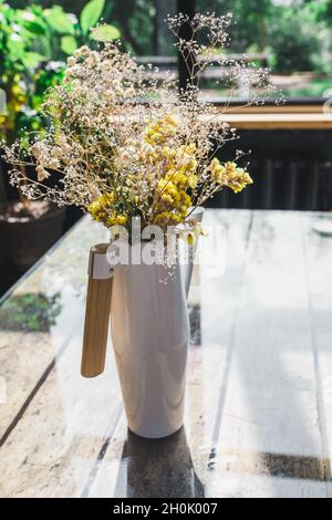 Beautiful wildflowers in jug on white wooden table indoors, closeup ...